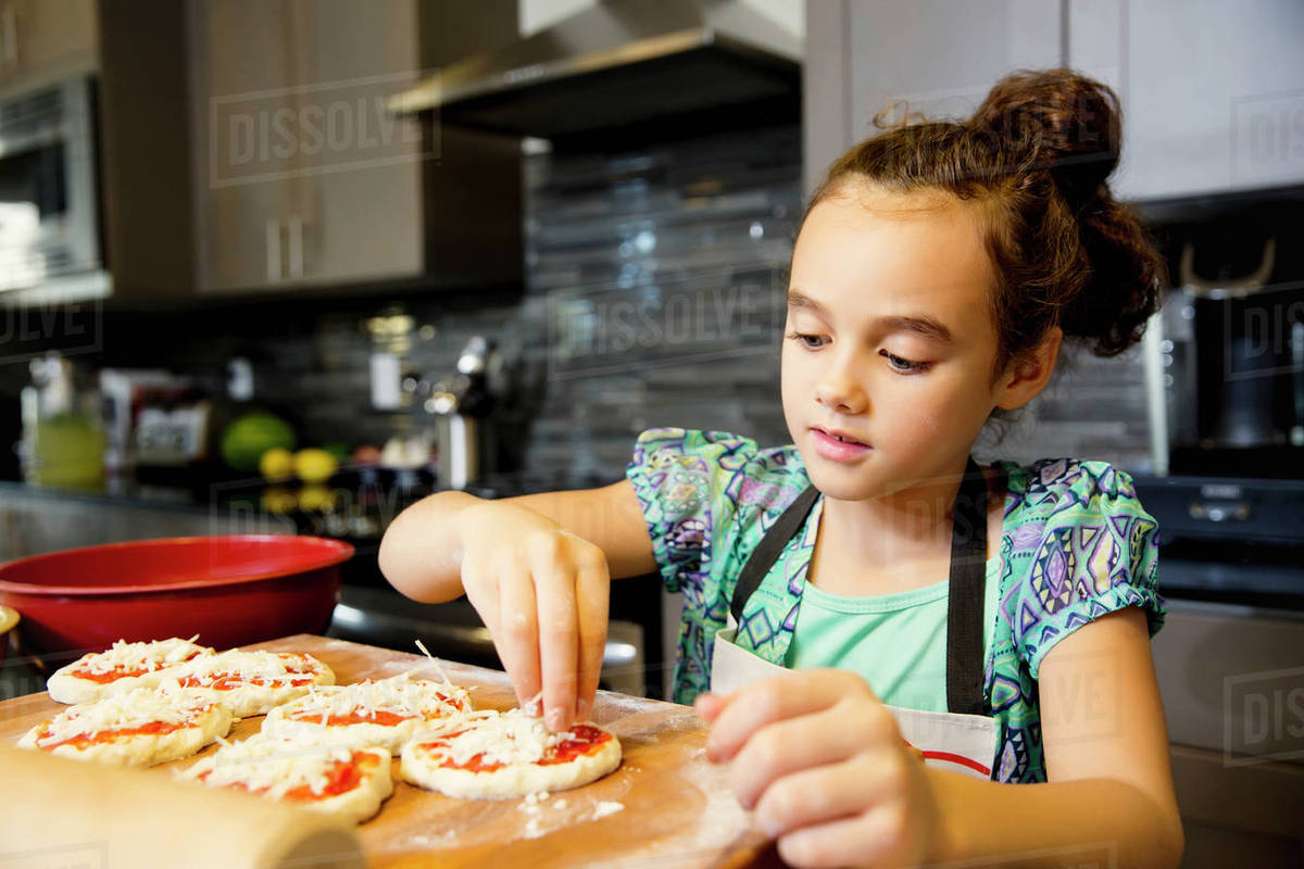 Mixed race girl cooking in kitchen - Royalty-free Stock Photo | Dissolve