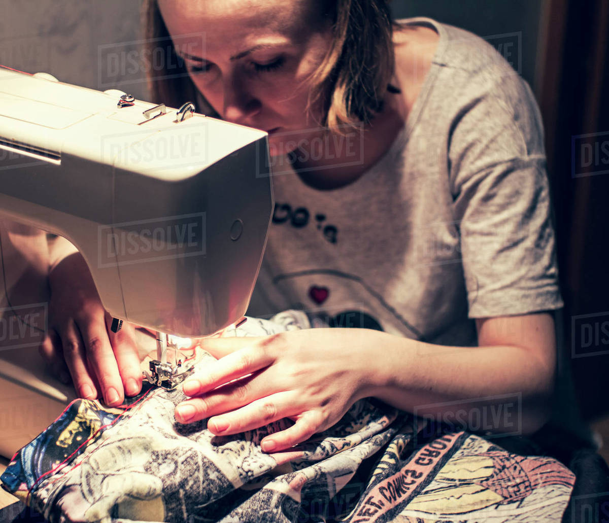 Caucasian woman using sewing machine - Stock Photo - Dissolve
