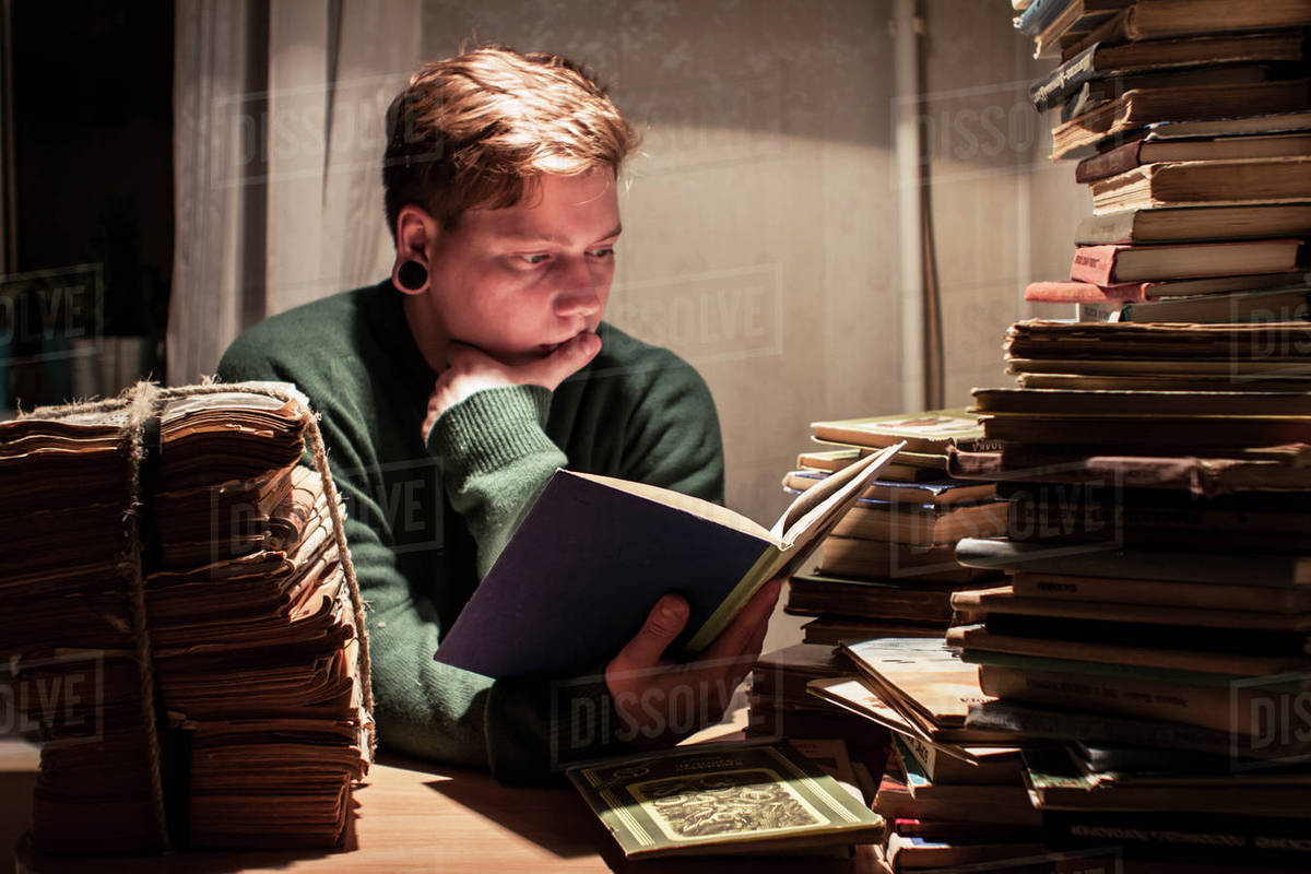 Caucasian man reading stack of books - Stock Photo - Dissolve