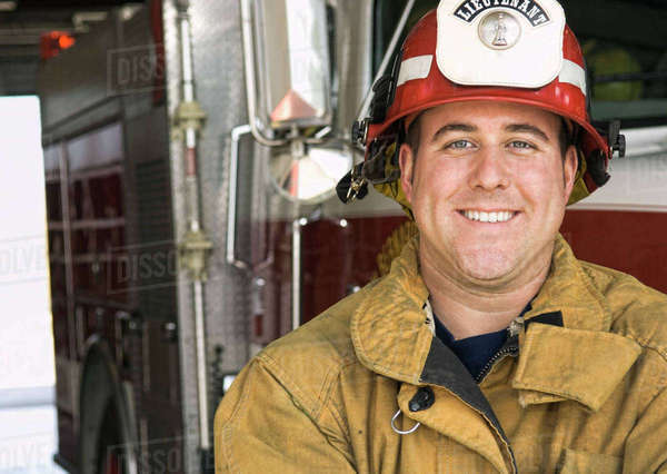 Caucasian firefighter smiling near fire truck - Royalty-free Stock ...