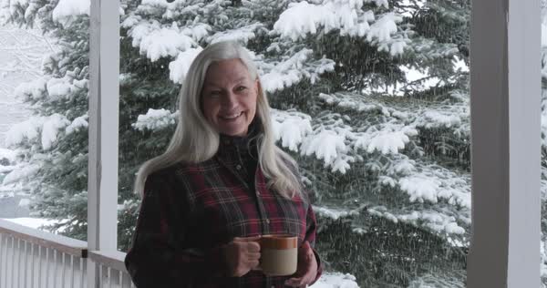 Woman drinking coffee on porch watching snow - Stock Video Footage ...