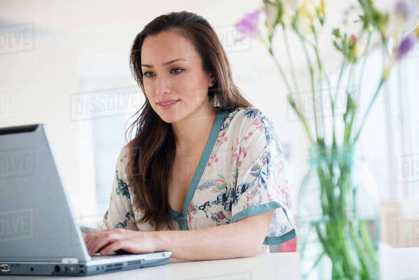 Woman using laptop at desk - Stock Photo - Dissolve