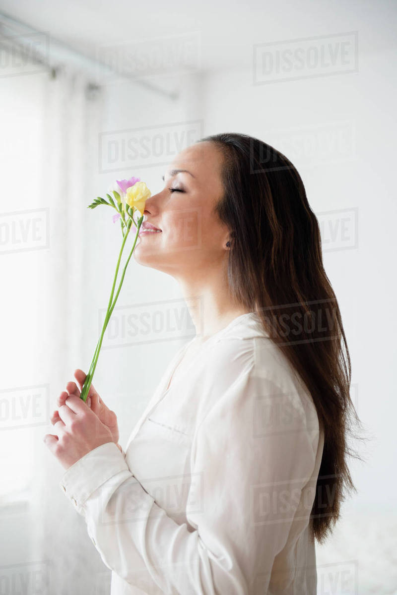 Woman smelling flowers indoors - Royalty-free Stock Photo | Dissolve