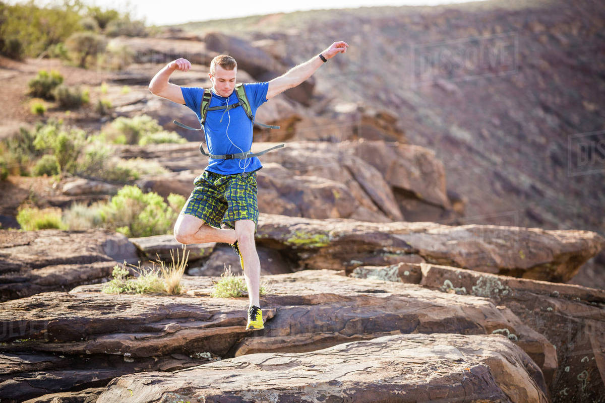 Caucasian teenage boy running on rock formation - Royalty-free Stock ...
