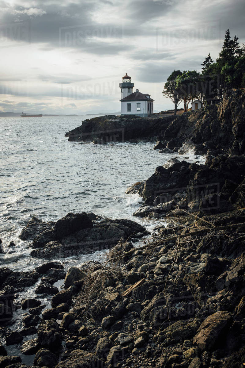 Distant lighthouse on rocky beach - Royalty-free Stock Photo | Dissolve