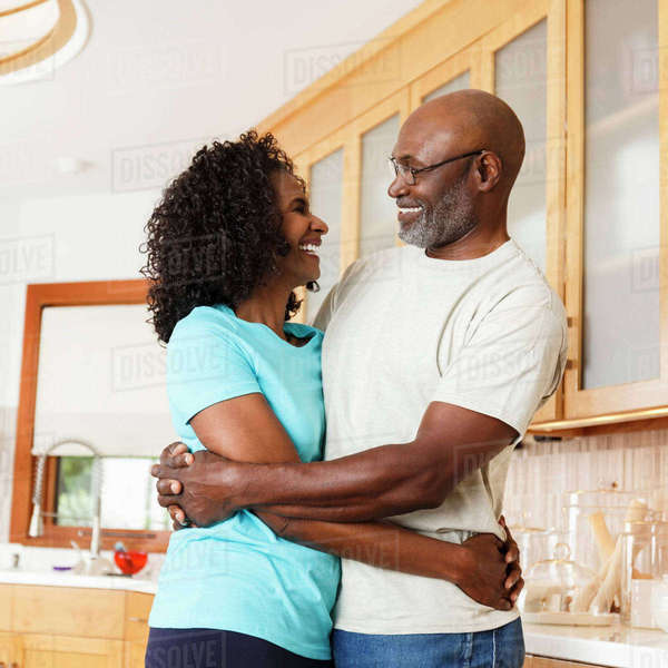 Black couple hugging in kitchen - Royalty-free Stock Photo | Dissolve