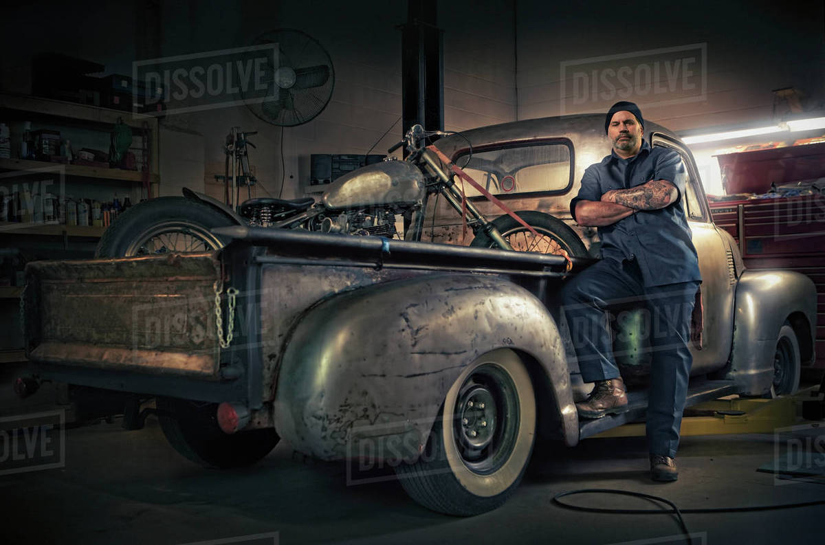 Caucasian mechanic posing on vintage truck with motorcycle - Royalty ...