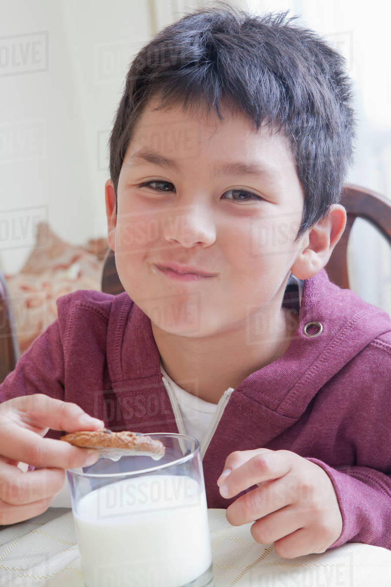 Hispanic boy eating cookie with milk at table - Royalty-free Stock ...