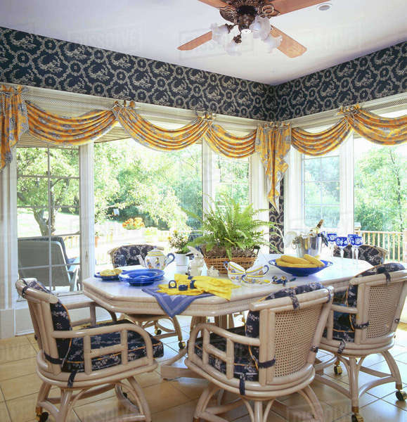 Dining table and chairs arranged in sunroom of traditional home ...