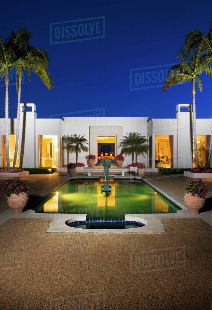 Evening exterior of a large white modern house with a swimming pool ...