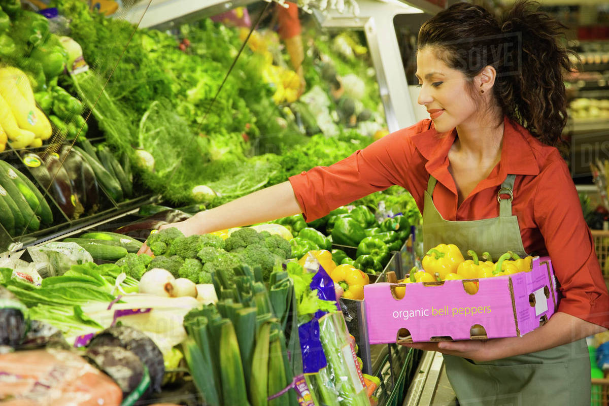 Hispanic woman working in produce section of grocery store - Royalty ...