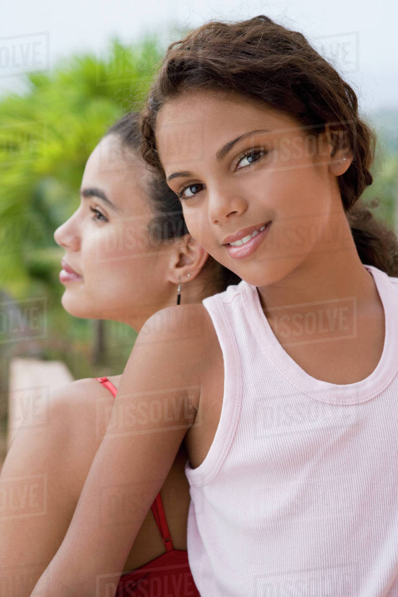 Hispanic girl back to back with young woman - Stock Photo - Dissolve
