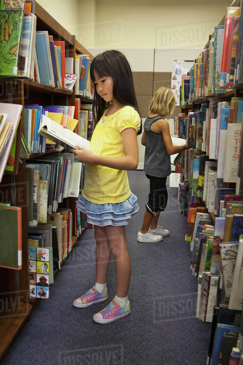 Girls reading books in library - Stock Photo - Dissolve