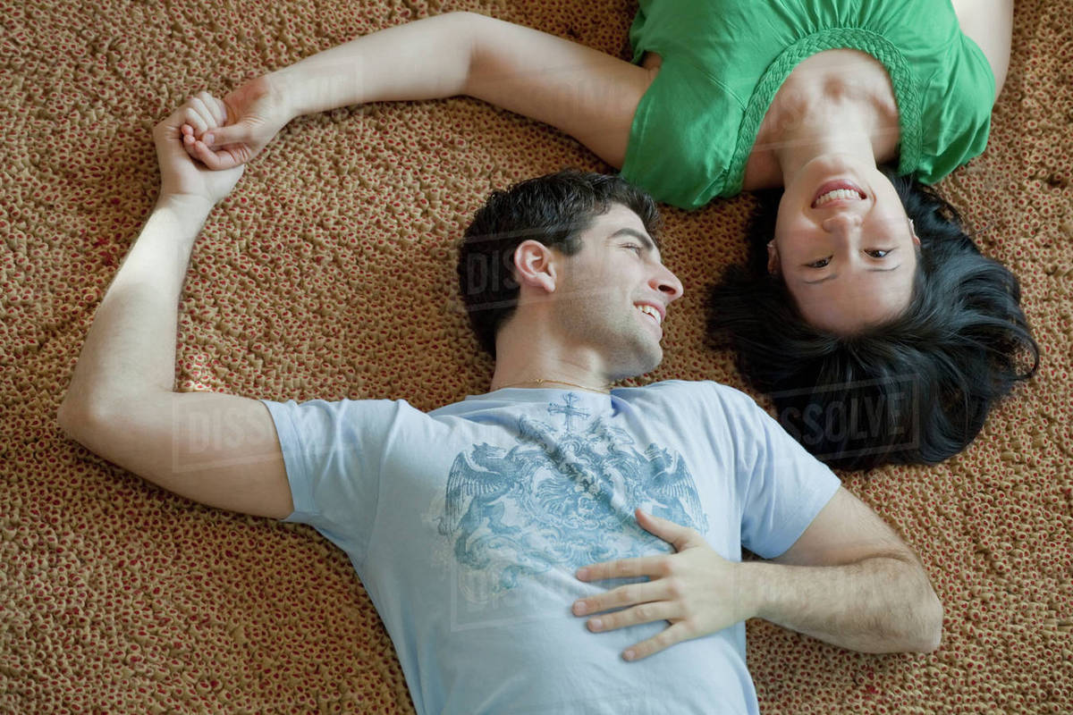 Couple laying on floor holding hands - Royalty-free Stock Photo | Dissolve