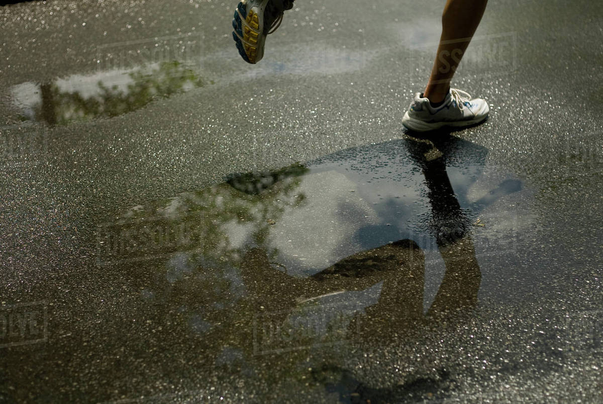Woman running through puddle - Royalty-free Stock Photo | Dissolve