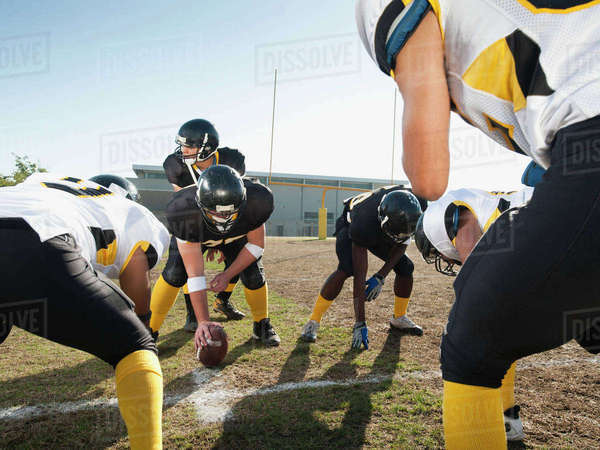 Football players crouching on football field - Stock Photo - Dissolve