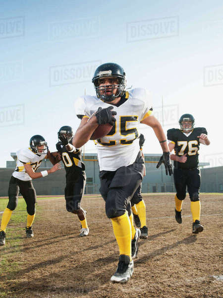 Football players playing on football field - Stock Photo - Dissolve