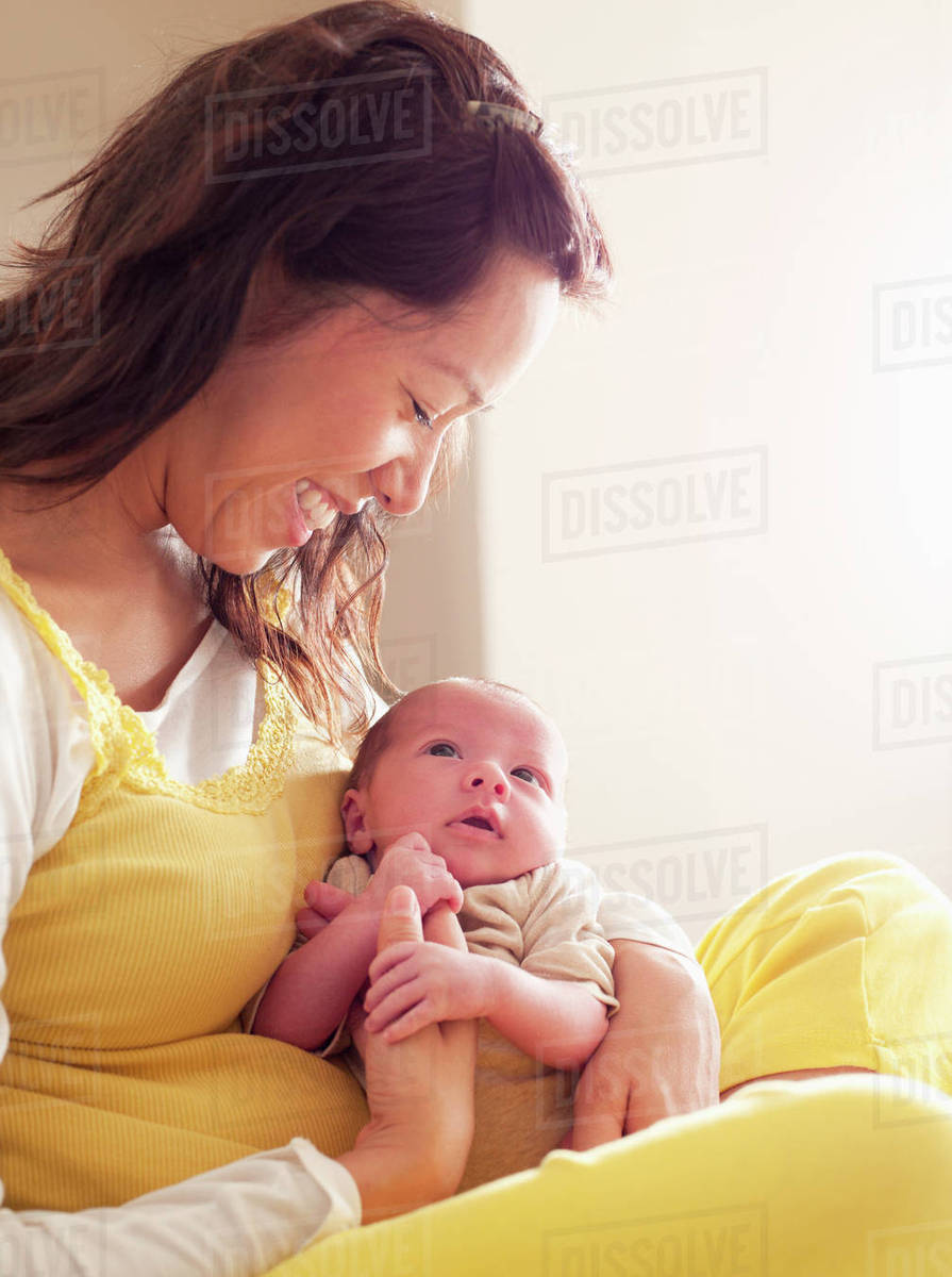 Mother holding newborn baby in her lap - Stock Photo - Dissolve