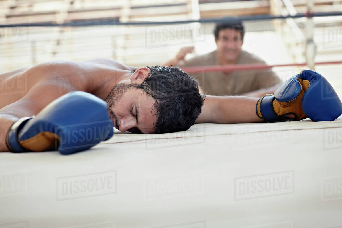 Knocked-out Hispanic boxer laying on ground - Stock Photo - Dissolve
