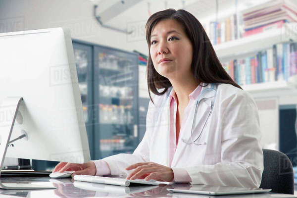 Asian doctor working at computer in hospital - Royalty-free Stock Photo ...