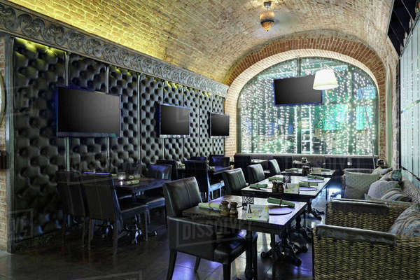 Restaurant interior with TV screens on leather covered wall - Stock ...
