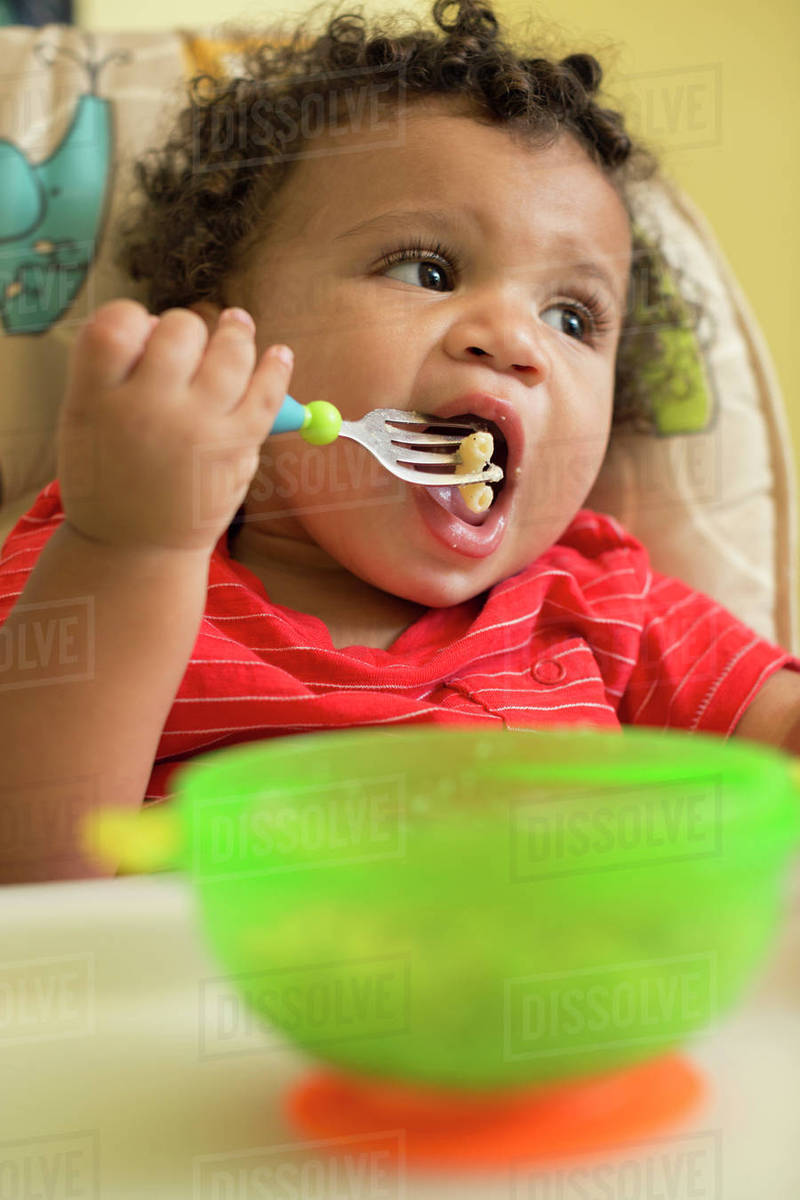 Mixed race toddler boy eating in high chair - Royalty-free Stock Photo ...