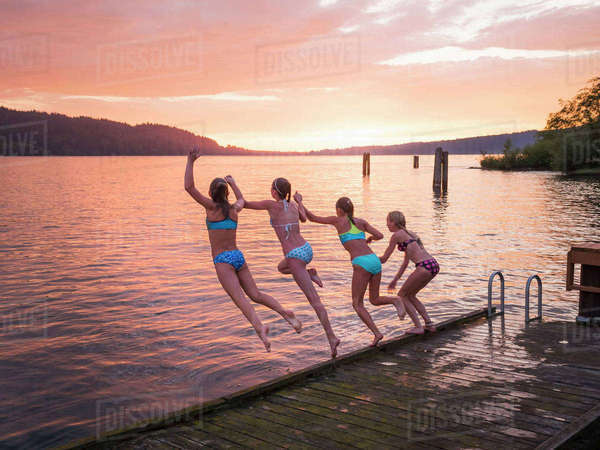 Girls jumping into lake from wooden dock - Royalty-free Stock Photo ...