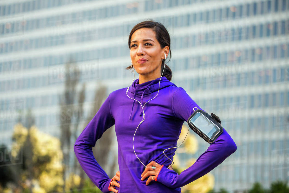 Hispanic runner standing near high rise building - Stock Photo - Dissolve