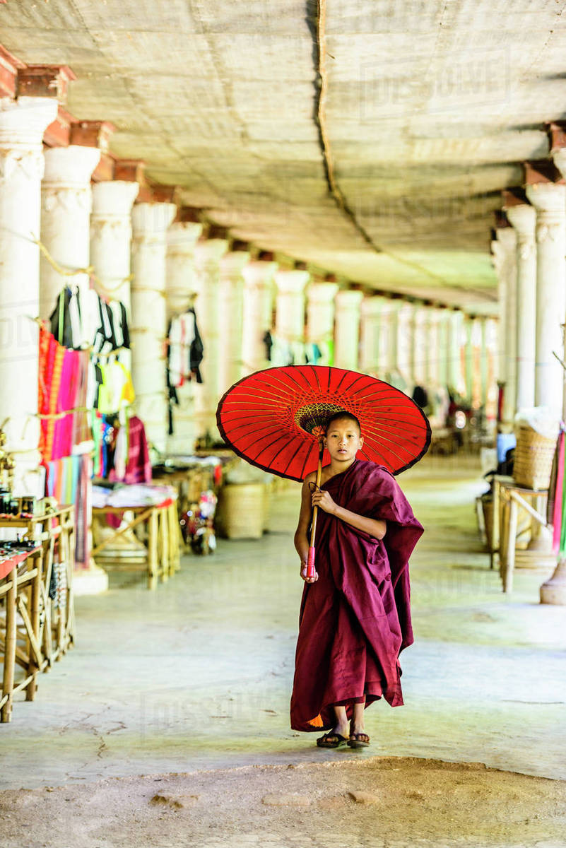 Asian monk-in-training with parasol walking in hallway - Royalty-free ...
