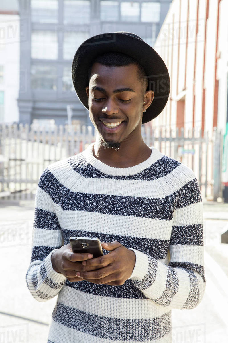 Black man using cell phone on urban sidewalk - Royalty-free Stock Photo ...
