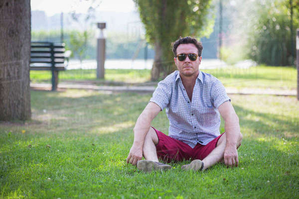 Caucasian man sitting in grass in park - Royalty-free Stock Photo ...