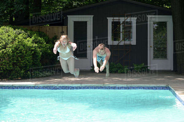 Couple diving into swimming pool in backyard - Stock Photo - Dissolve