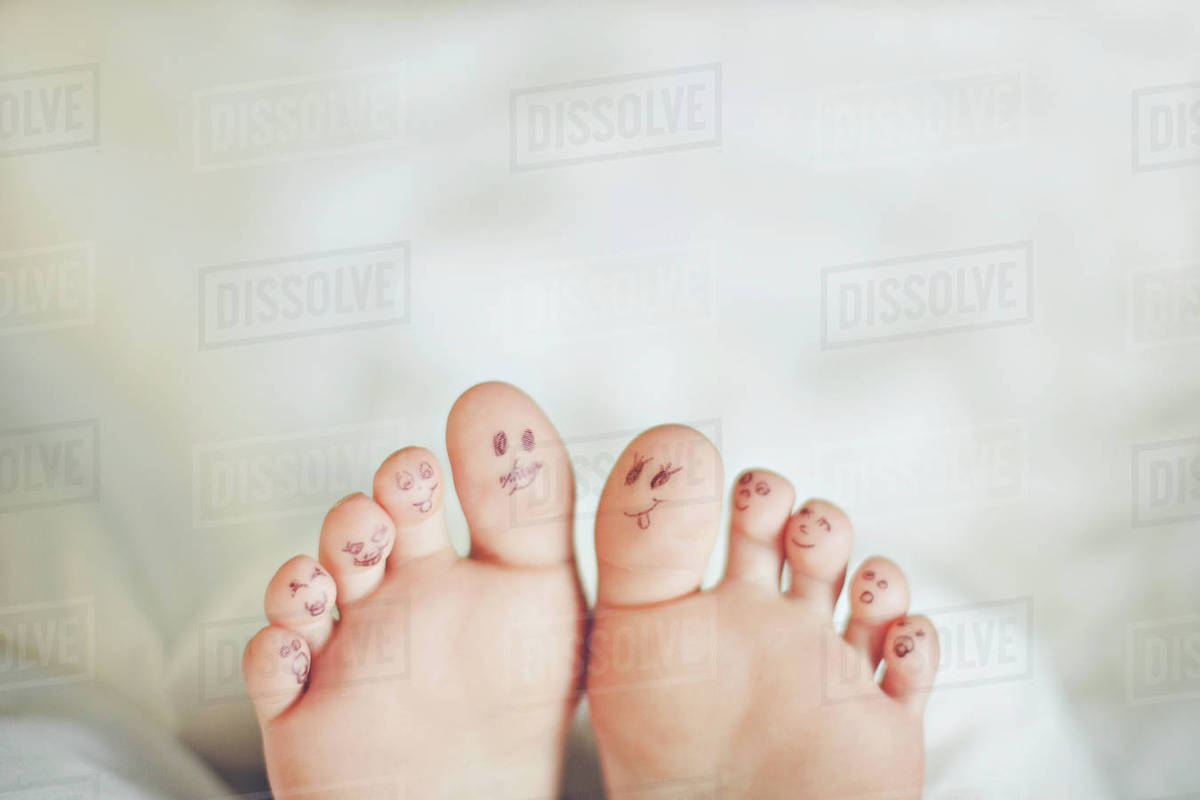 Toes of Caucasian girl with smiley face drawings - Stock Photo - Dissolve