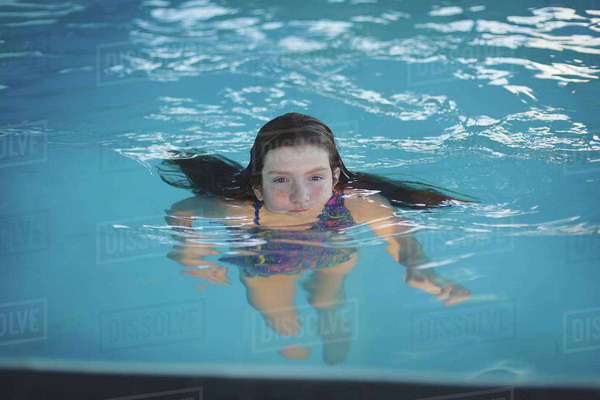 Caucasian girl floating in swimming pool - Stock Photo - Dissolve