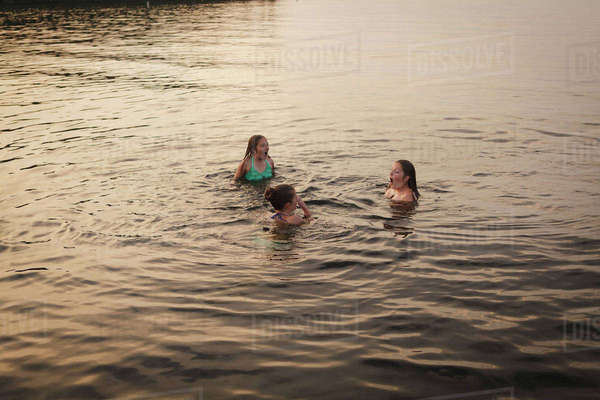 Caucasian girls swimming in lake - Stock Photo - Dissolve