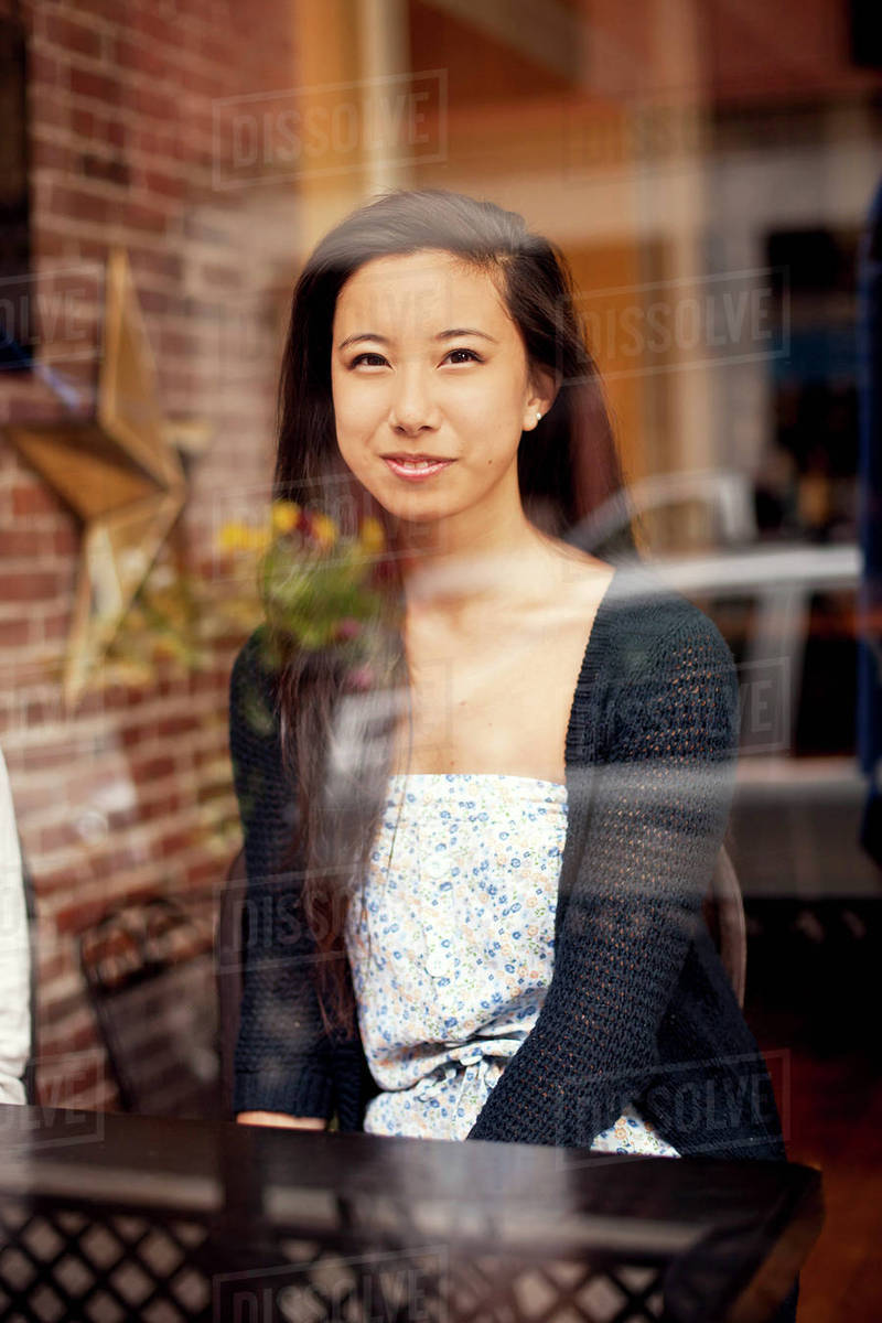 Woman smiling behind window in cafe - Stock Photo - Dissolve