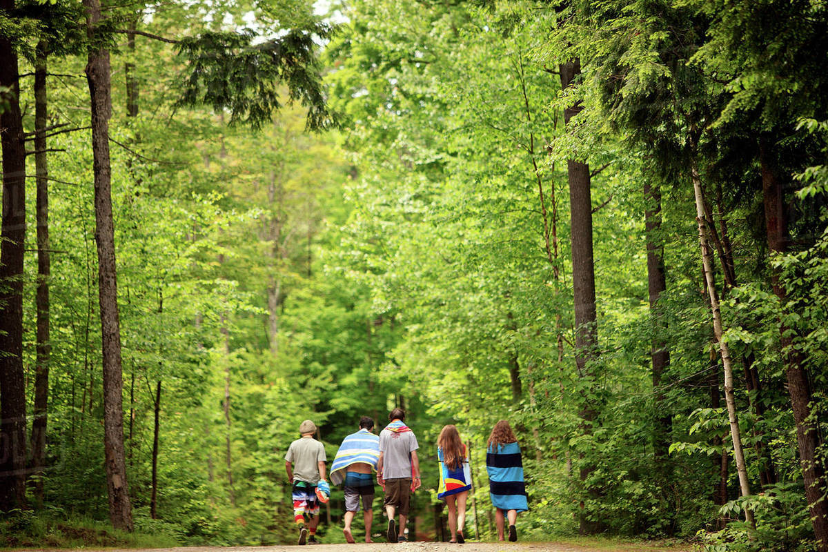 Friends walking on dirt path in forest - Stock Photo - Dissolve