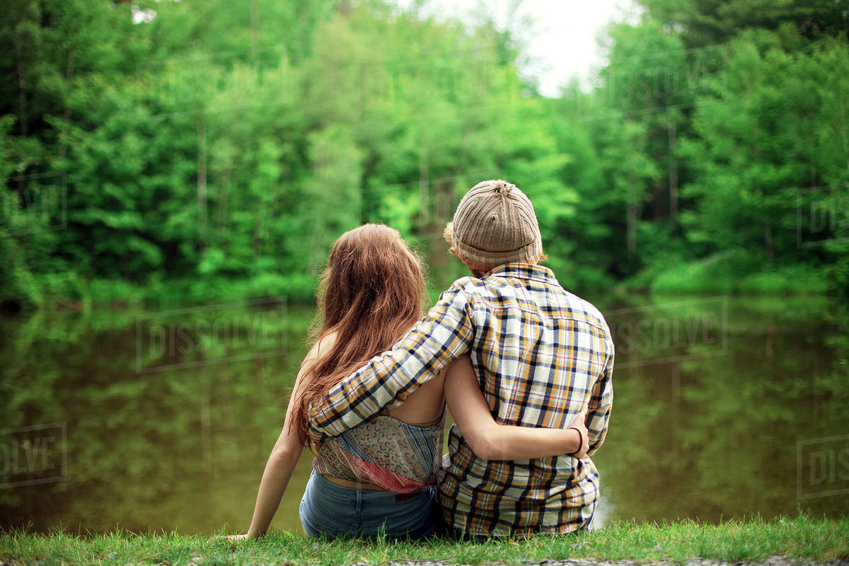 Rear view of couple hugging near lake - Stock Photo - Dissolve