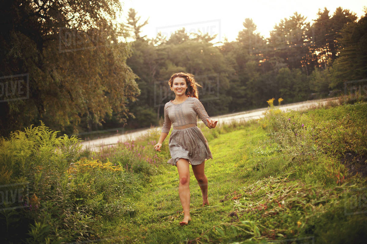 Smiling woman running in rural field - Stock Photo - Dissolve