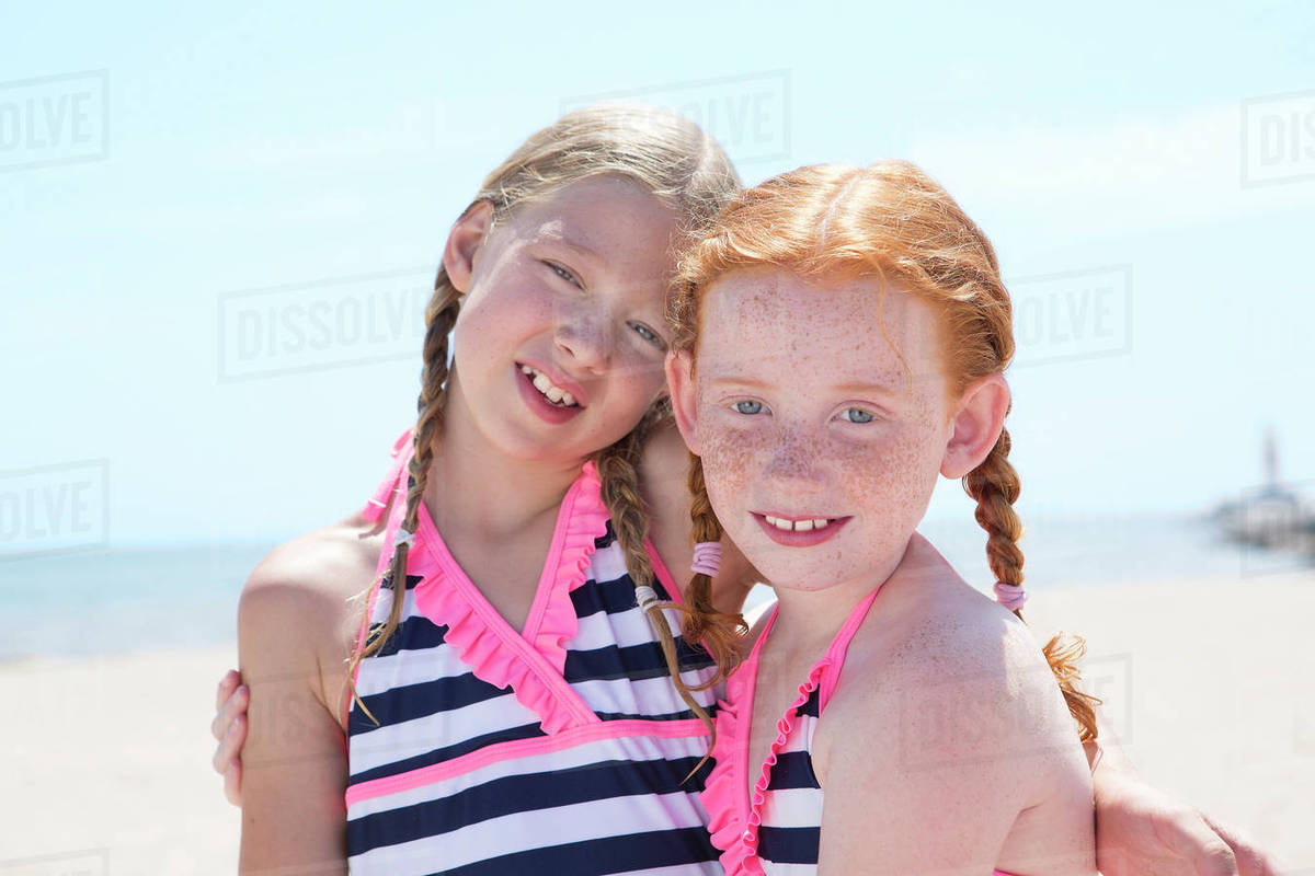 Caucasian girls hugging on beach - Stock Photo - Dissolve