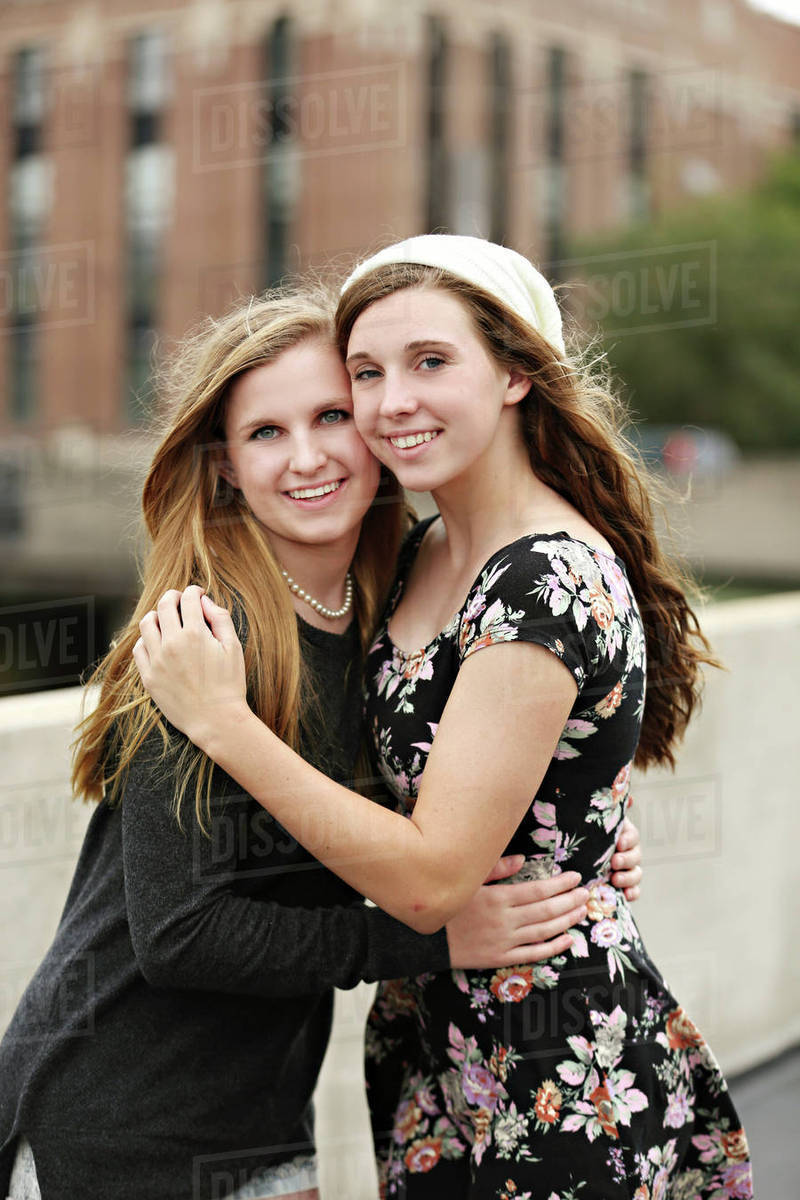 Smiling women hugging on urban rooftop - Stock Photo - Dissolve