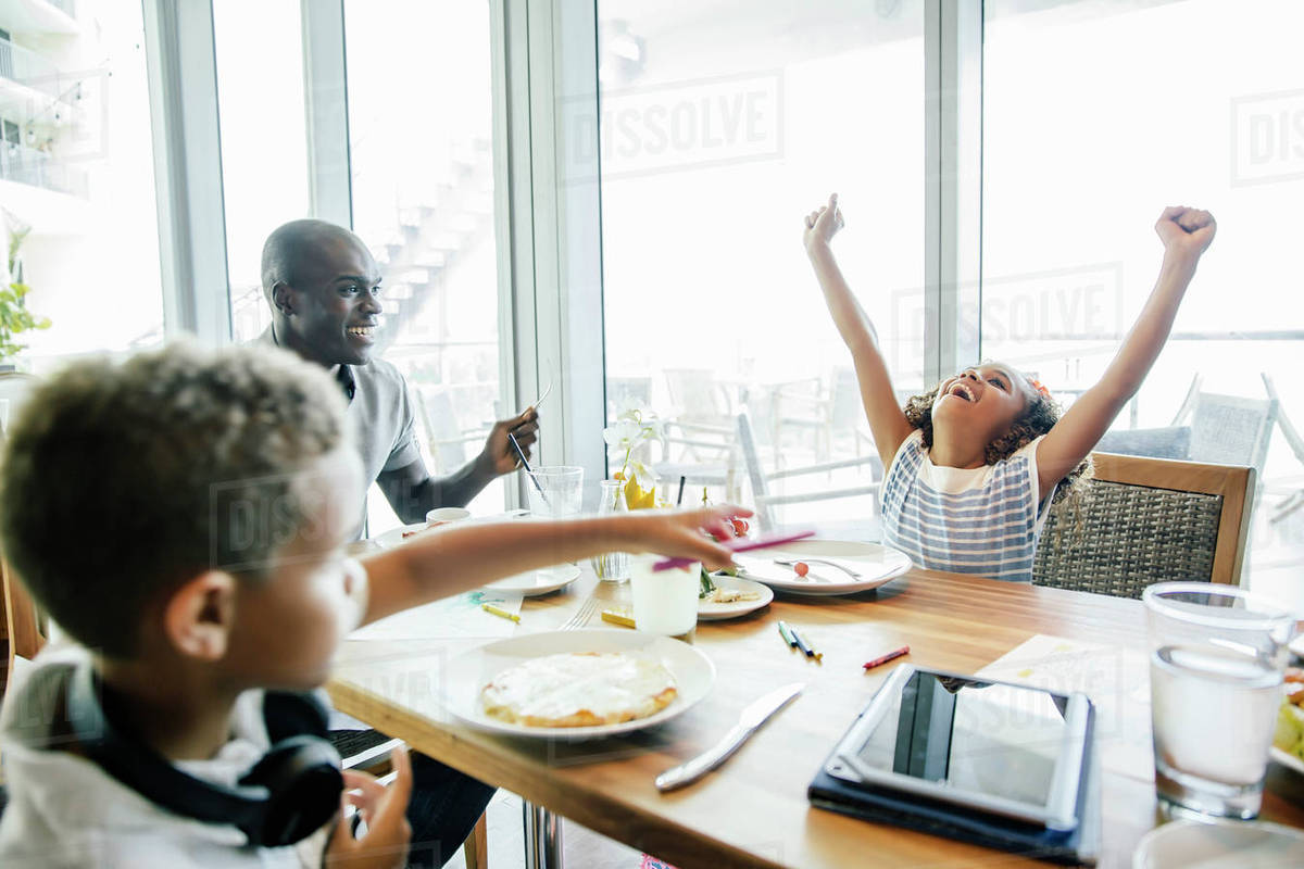 Girl cheering at table in restaurant - Royalty-free Stock Photo | Dissolve