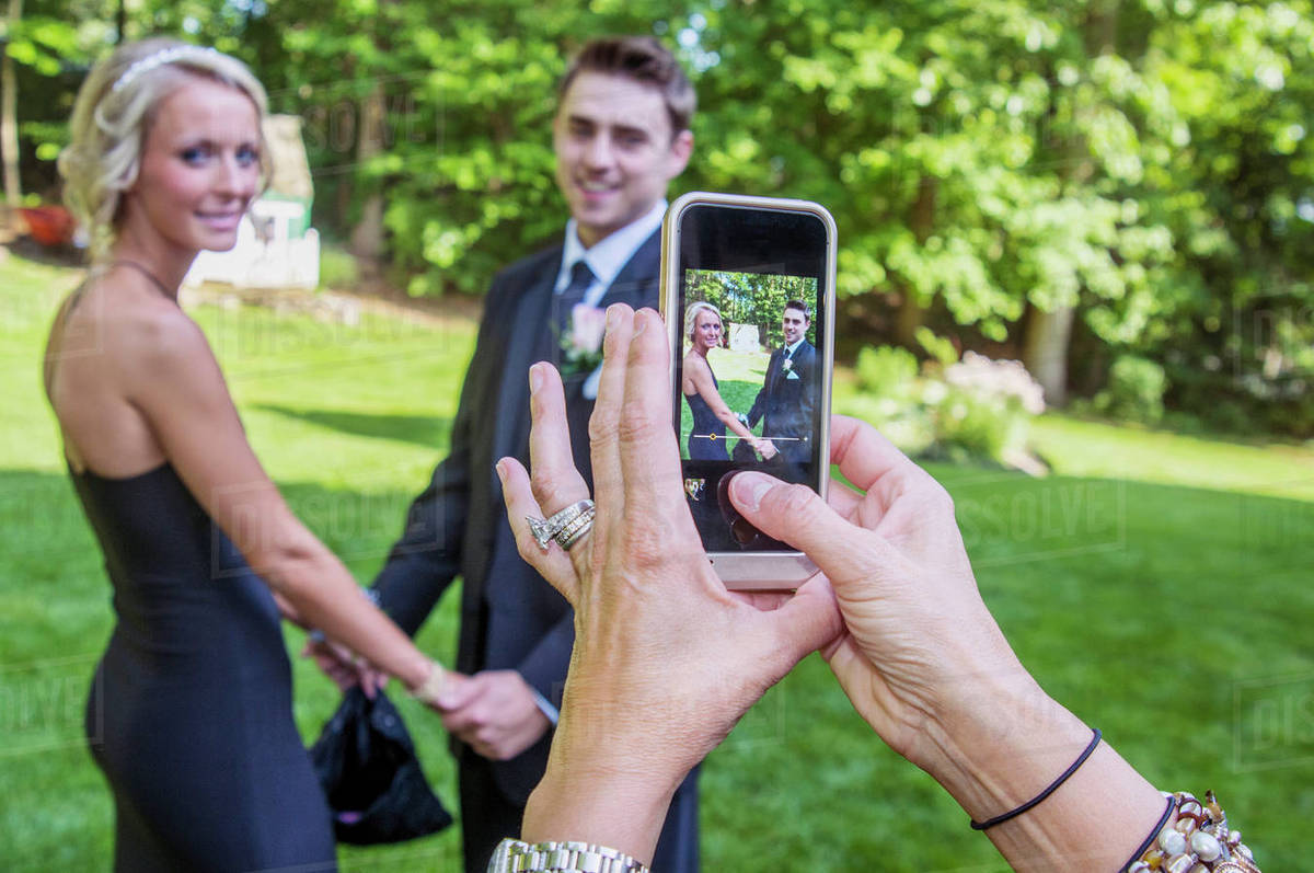 Woman taking cell phone photograph of couple - Stock Photo - Dissolve