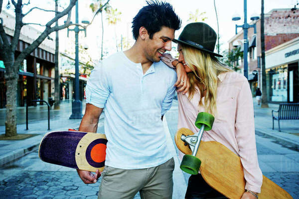 Caucasian couple carrying skateboards - Stock Photo - Dissolve