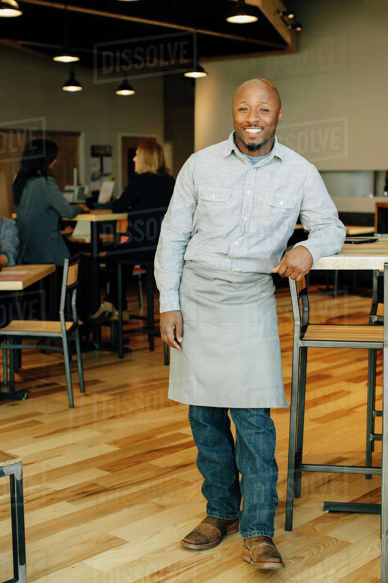 Black waiter smiling in in cafe - Royalty-free Stock Photo | Dissolve