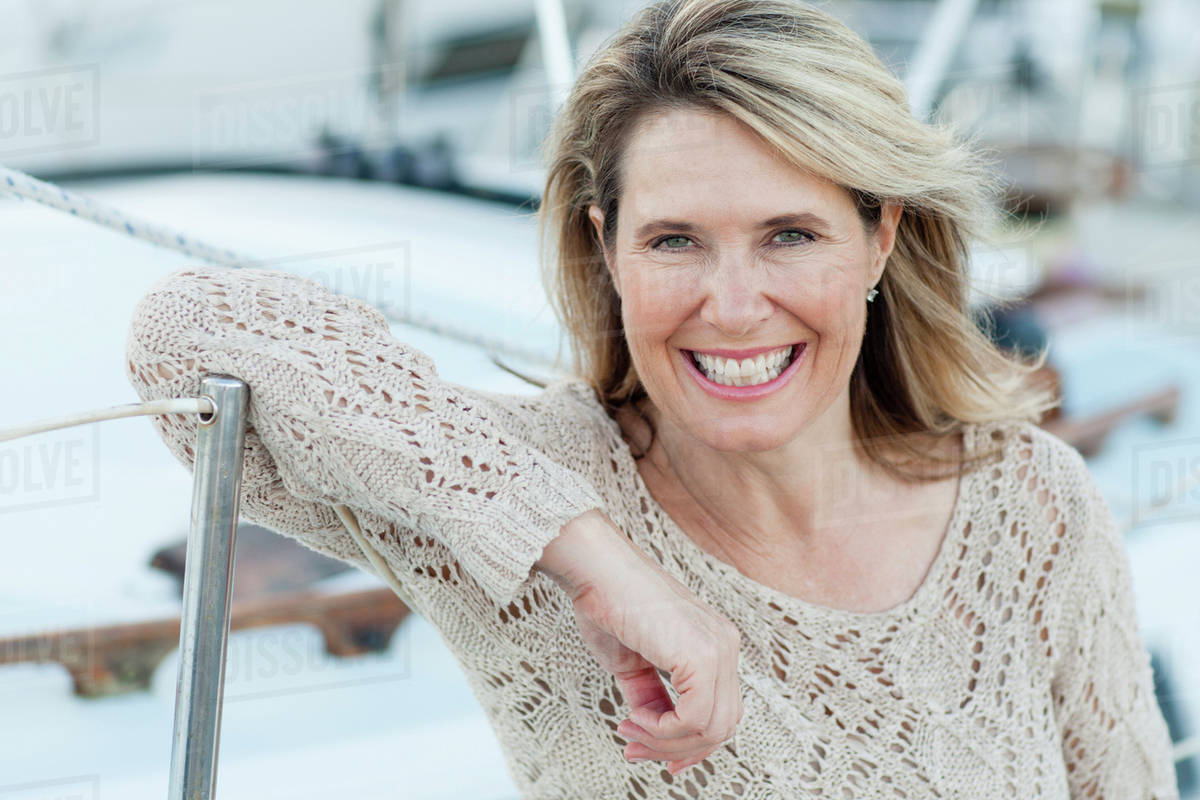 Caucasian woman leaning on boat in harbor - Stock Photo - Dissolve