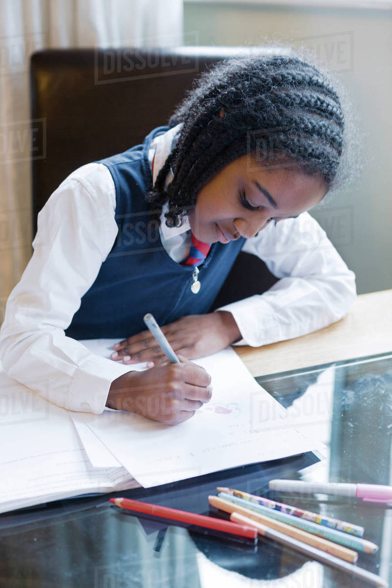 Black girl wearing school uniform doing homework - Stock Photo - Dissolve