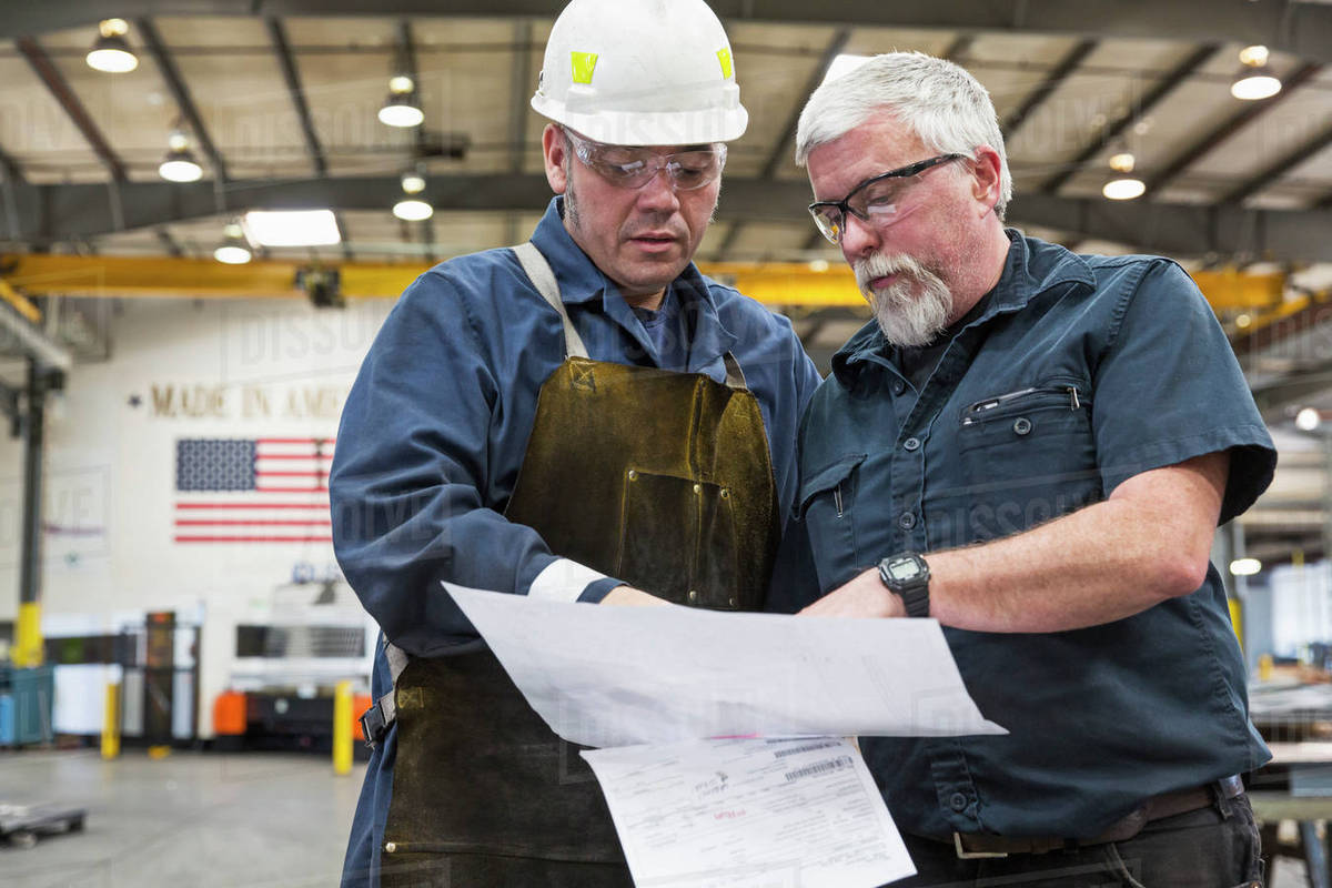 Workers reading paperwork in factory - Stock Photo - Dissolve
