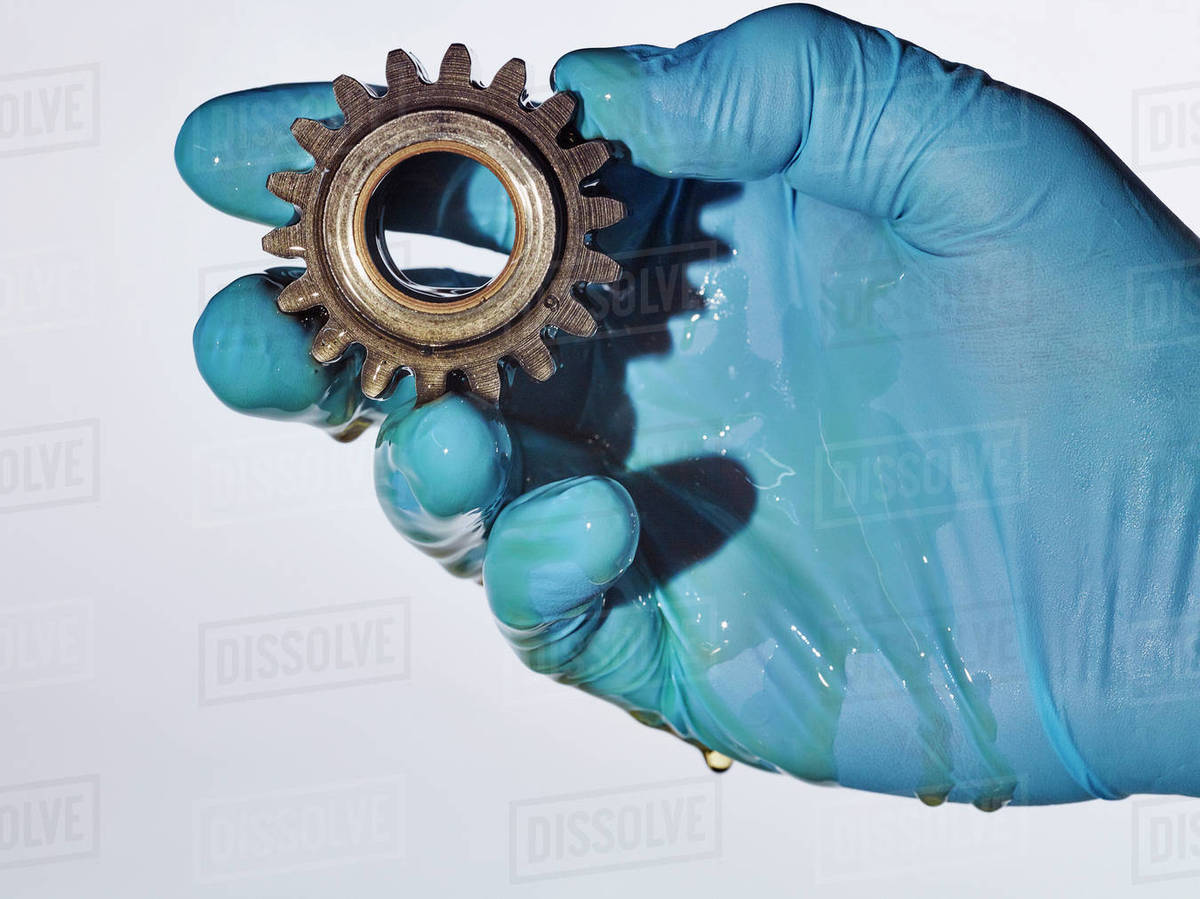 Hand wearing rubber-glove holding gear dripping with oil - Stock Photo ...