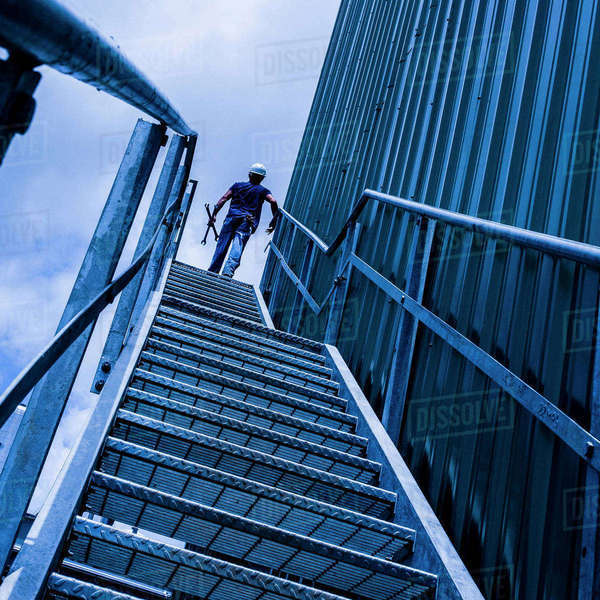 Caucasian worker carrying tools on staircase - Stock Photo - Dissolve